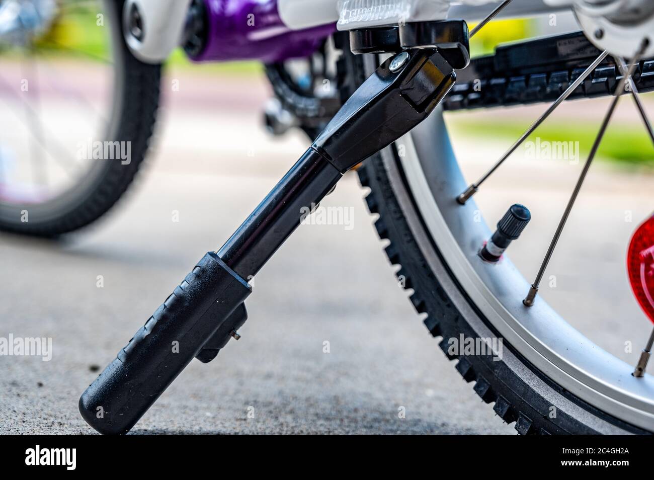 Metal kick stand extended to support a parked bike on a concrete ...