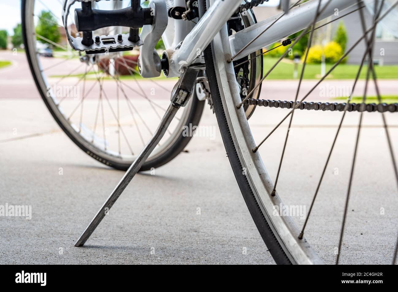 Metal kick stand extended to support a parked bike on a concrete ...