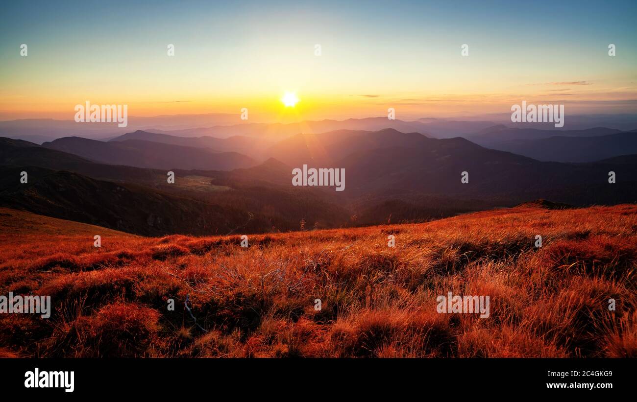 Beautiful vibrant sunset over the mountain peaks and hills panorama ...