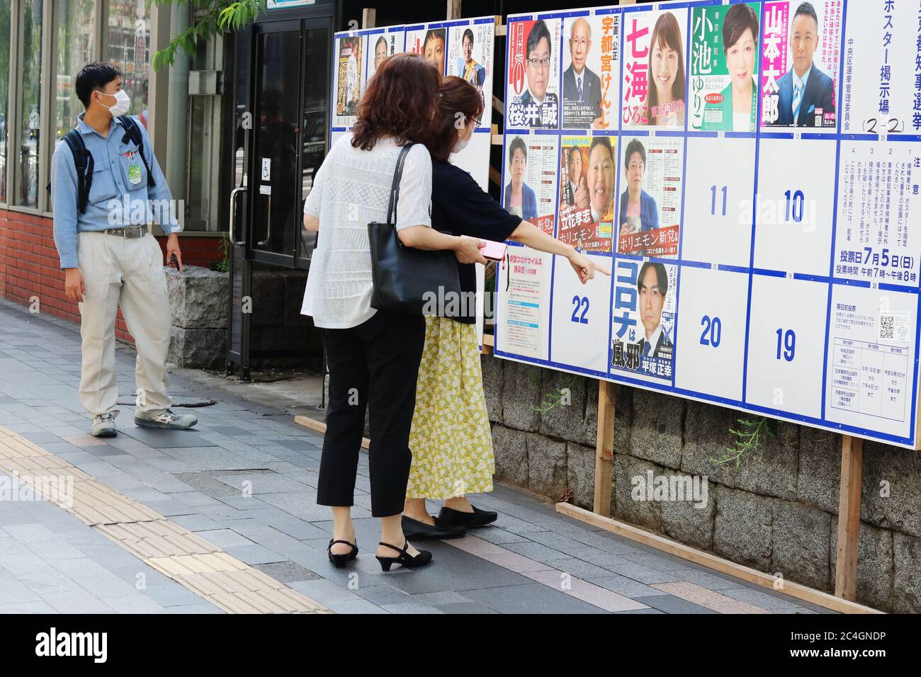 People wearing face masks look at posters of candidates in upcoming ...