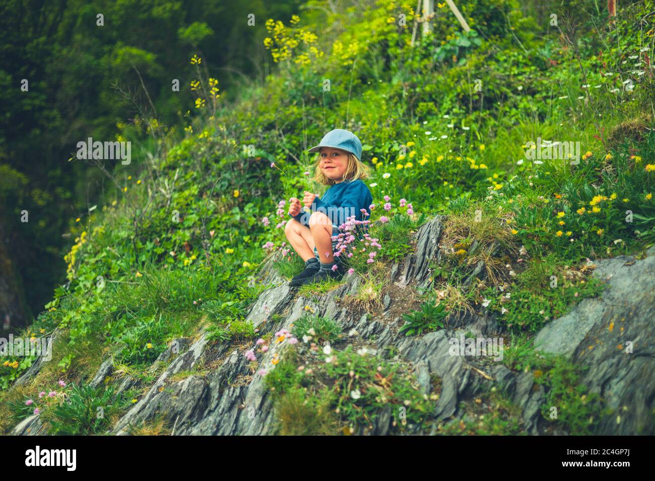 A little preschooler boy is sitting on a cliff Stock Photo - Alamy