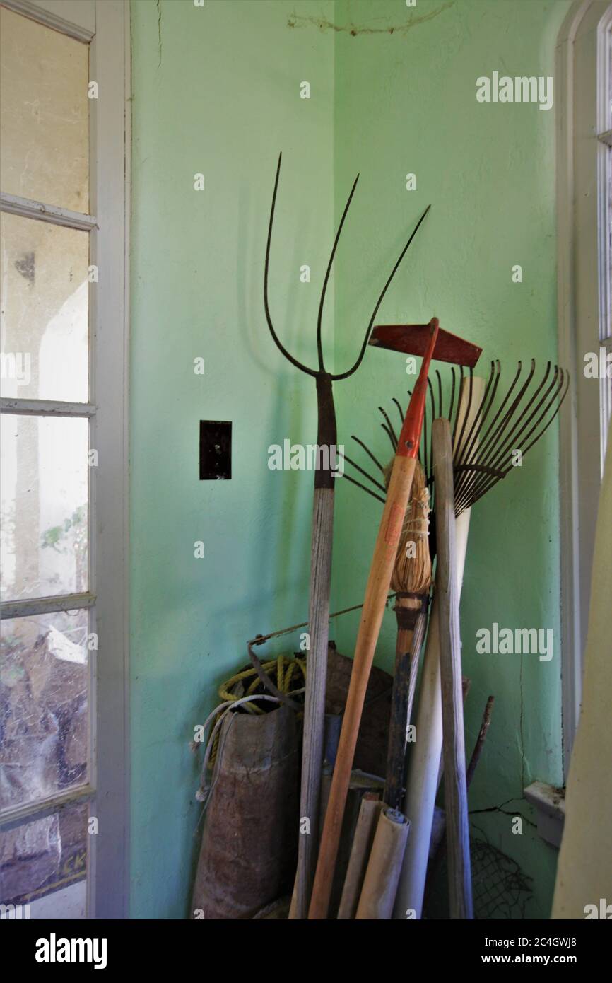 Old time yard hand tools leaning in corner of room where old farming ...