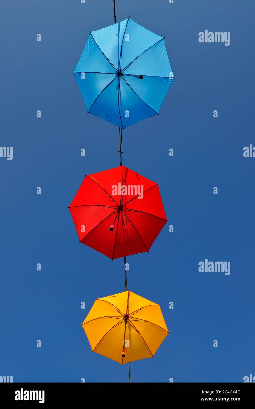 Low angle view of three different colored umbrellas red, orange and ...