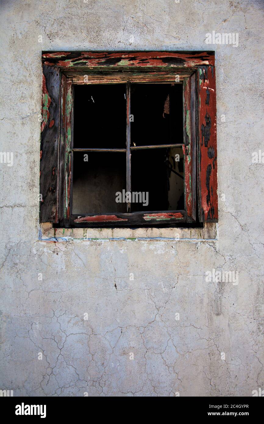 rotting window in exterior wall of abandoned building with worn red ...