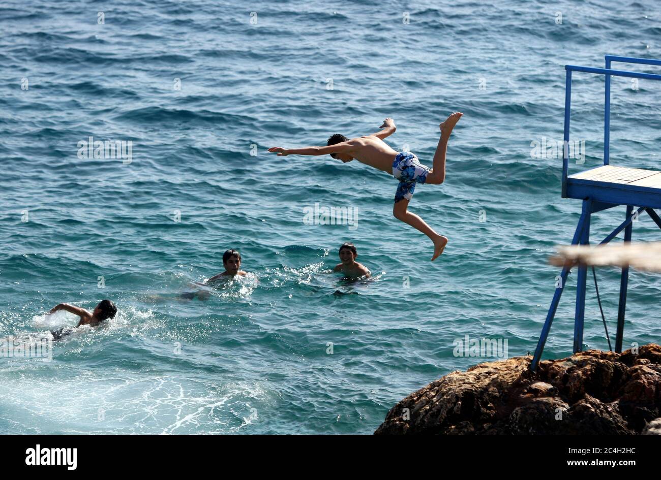 A Turkish boy dives from a platform into the Mediterranean Sea at Kas ...