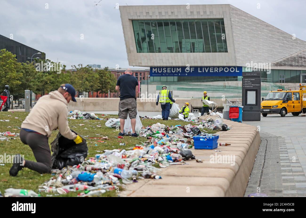 Workmen clear up rubbish left outside the Liver building in Liverpool ...