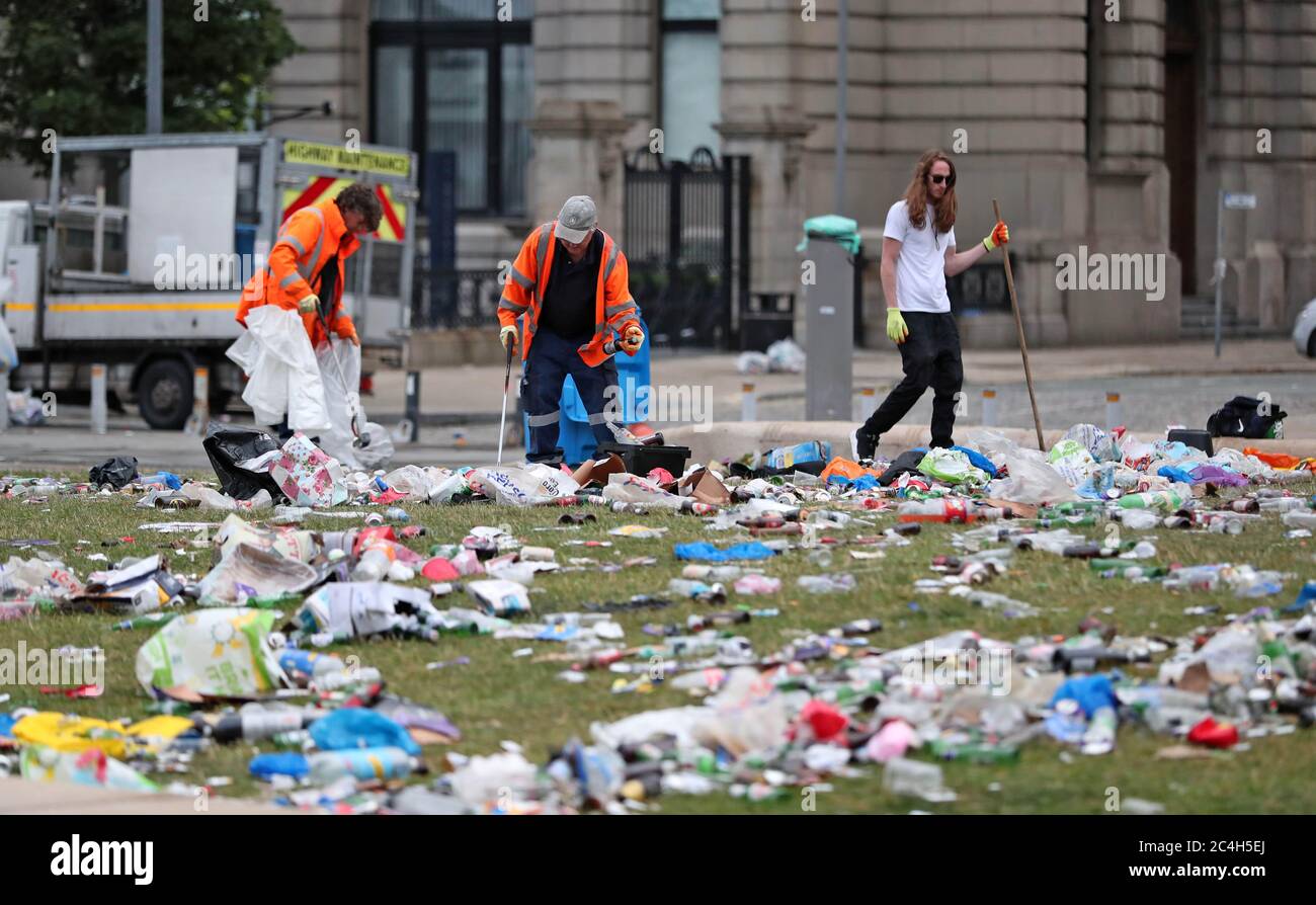 Workmen clear up rubbish left outside the Liver building in Liverpool ...