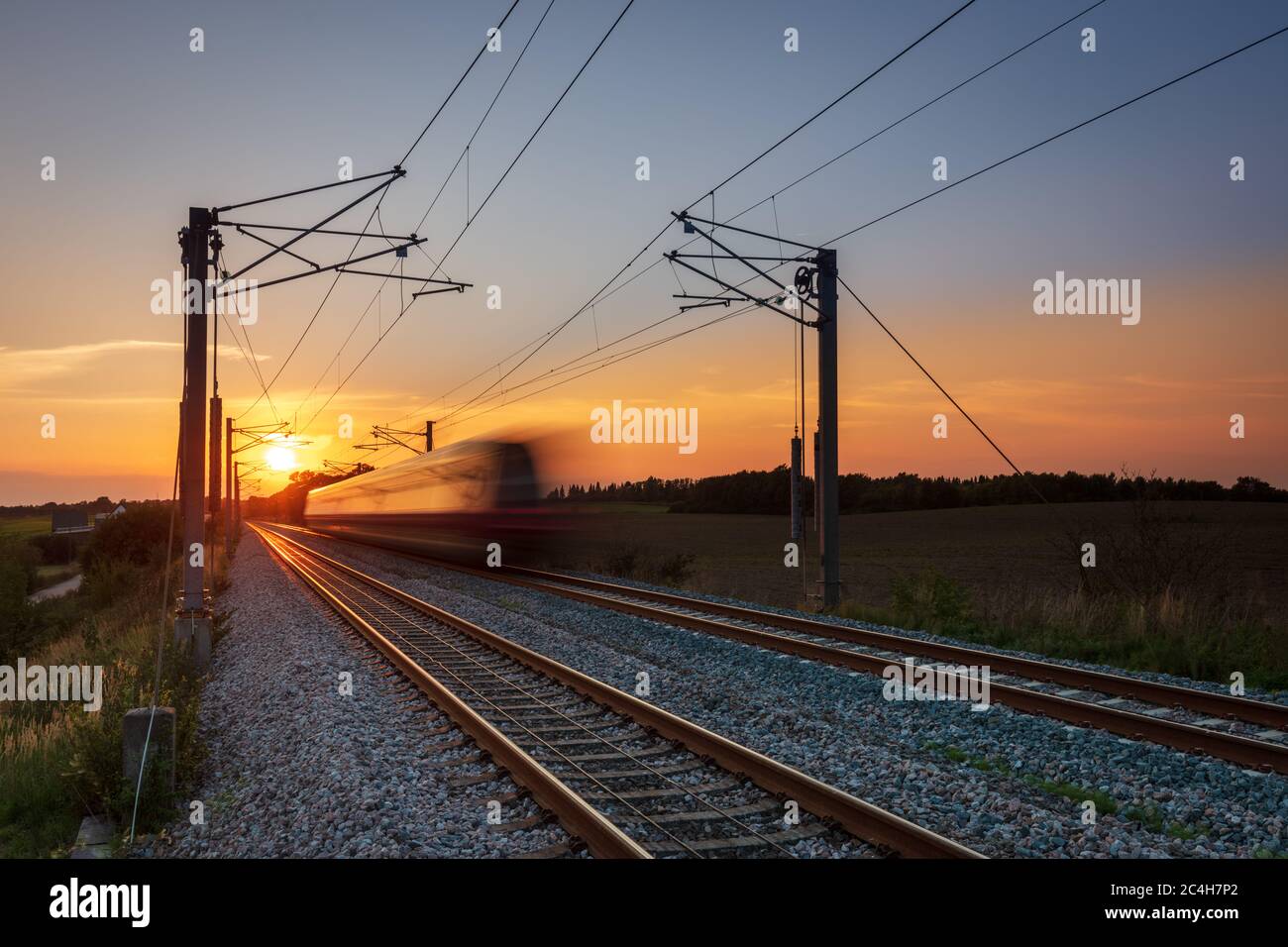 A local commuter train passing a field outside Copenhagen at a summer ...