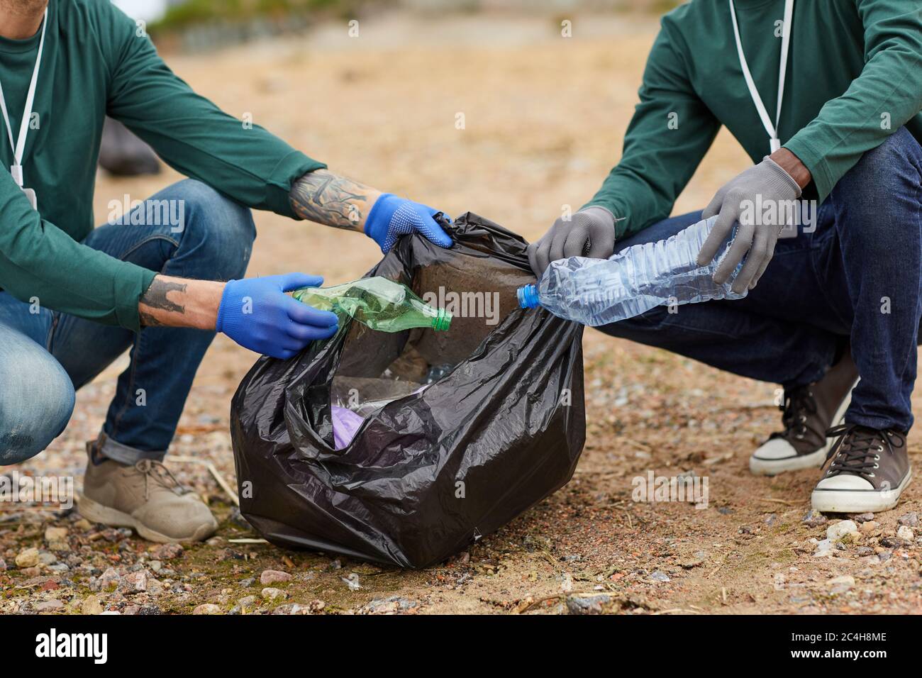 Close-up of people putting the garbage into the big black bags outdoors ...