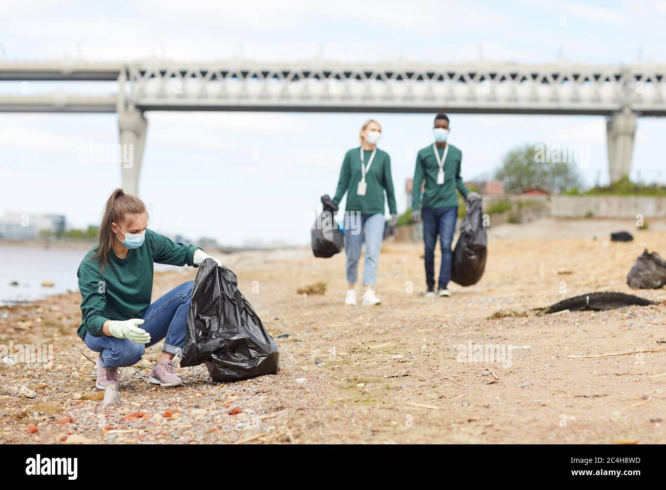 Group of volunteers picking up the rubbish near the bank of the river ...