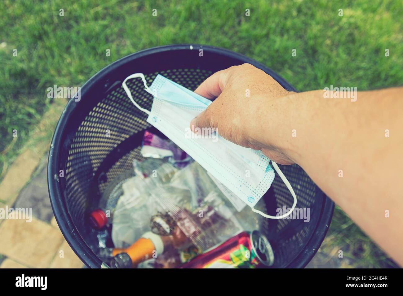Man throwing face masks into trash in park. Man throwing used surgical ...