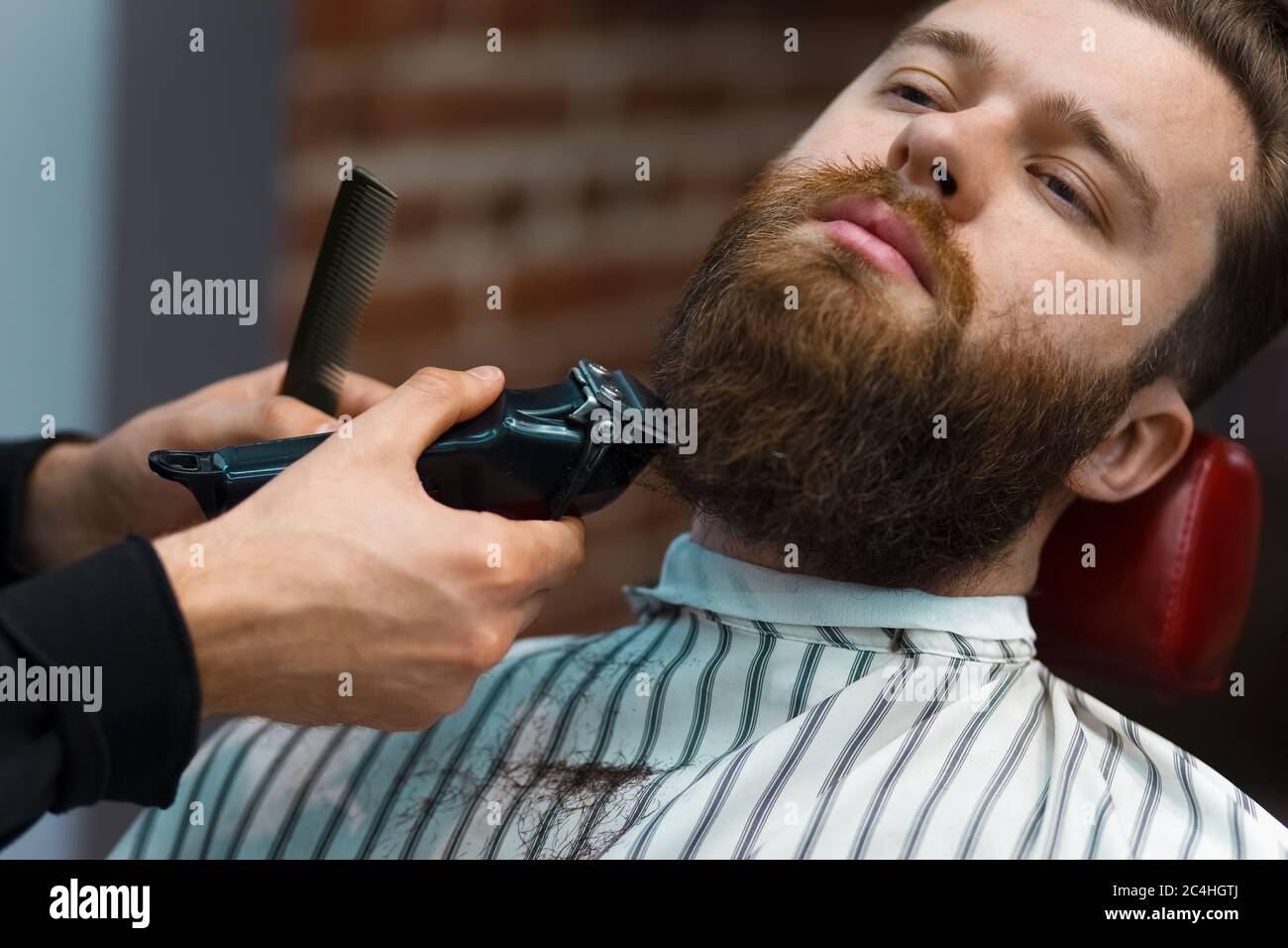 Barber master cuts beard to a brutal guy Stock Photo - Alamy