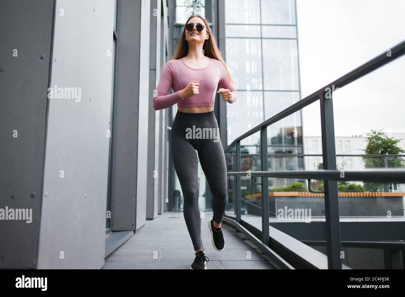Beautiful sports girl runs near a modern building Stock Photo - Alamy