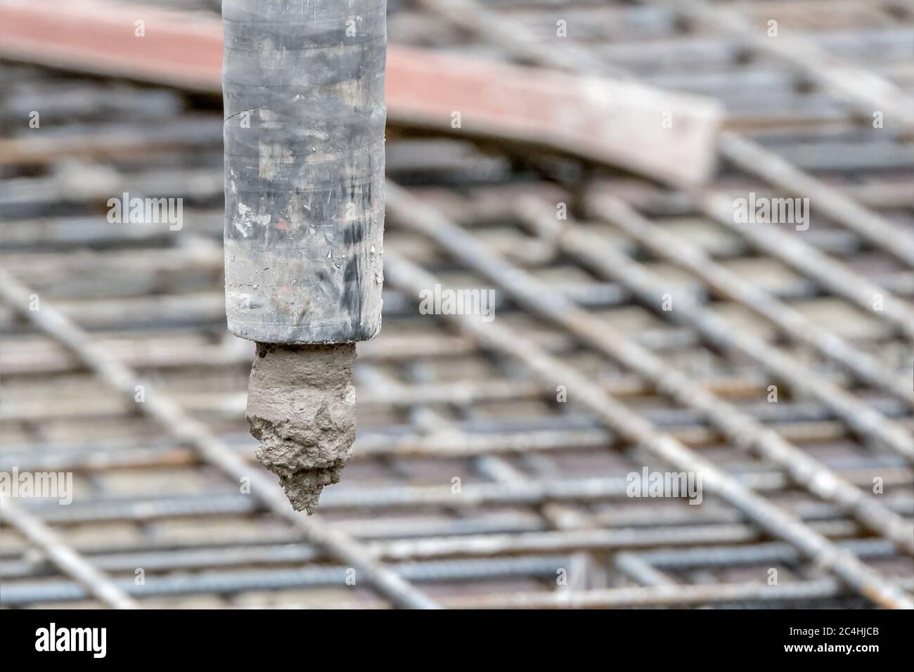 Wet concrete dripping from a large hose. Lots of rebar in the ...