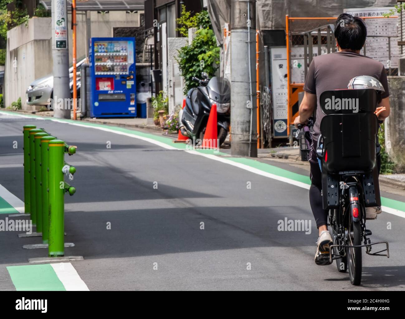 Japanese father riding a mamachari bicycle with his child in the street ...