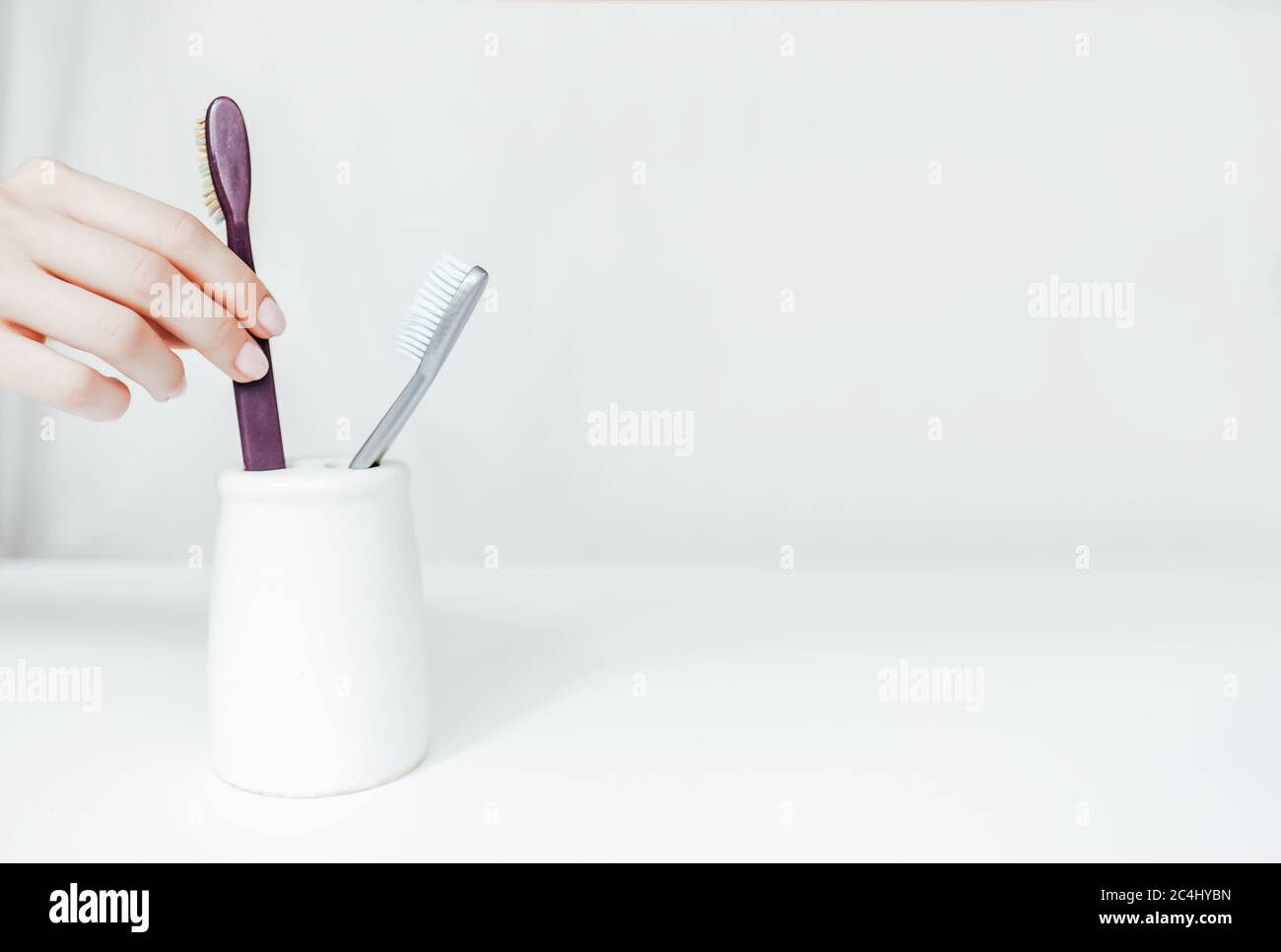 Hand takes a toothbrush from a white cup Stock Photo - Alamy
