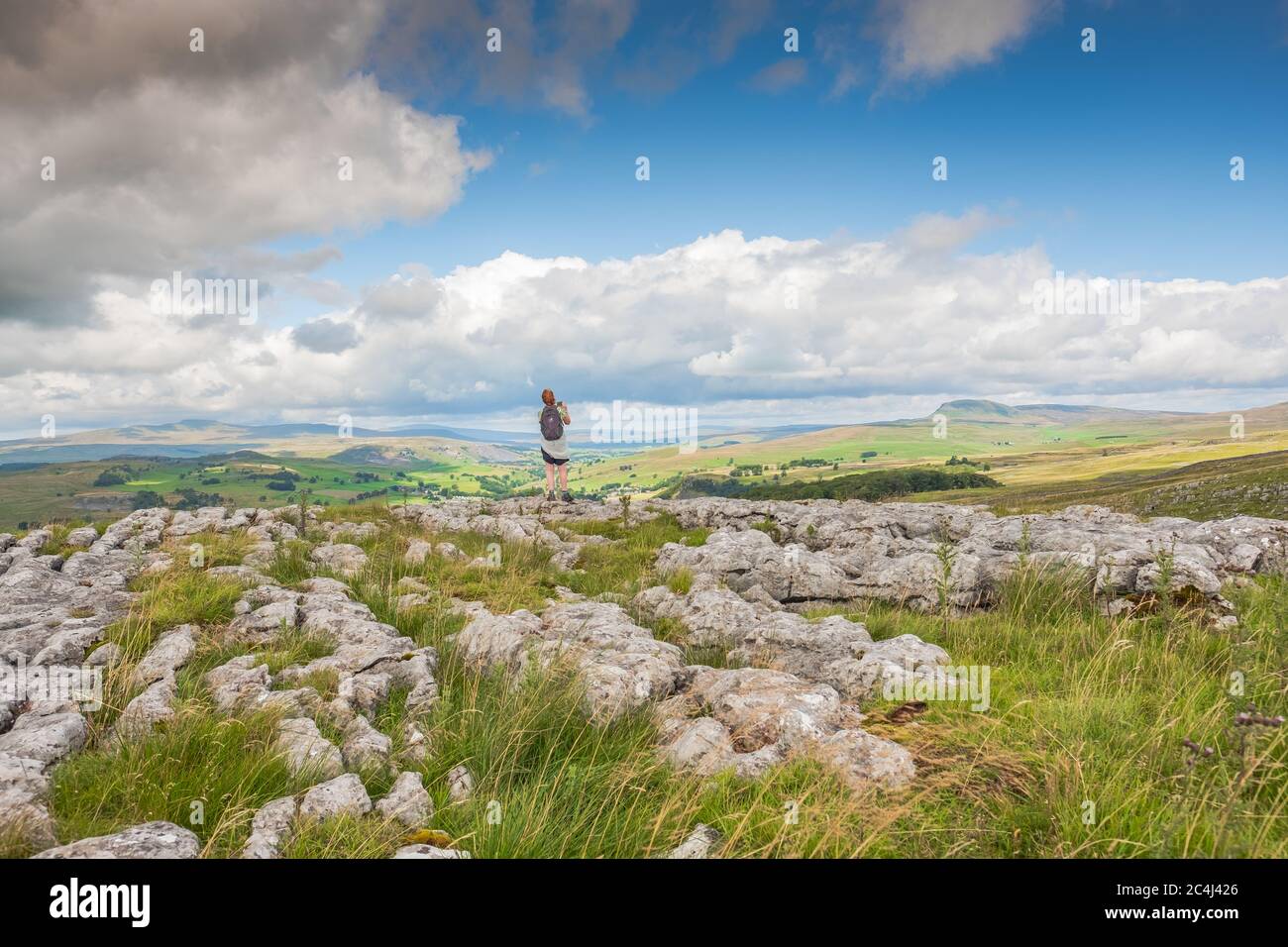Tourist seen taking images on a limestone rock formation, Malham Cove ...