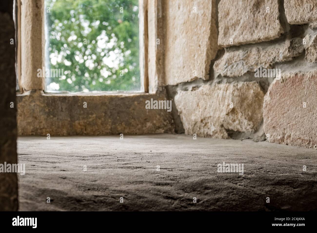 View looking out of a medieval, stonework window to a distant tower ...
