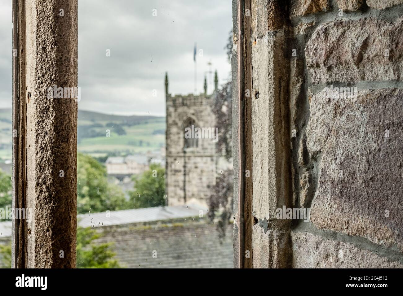 View looking out of a medieval, stonework window to a distant tower ...