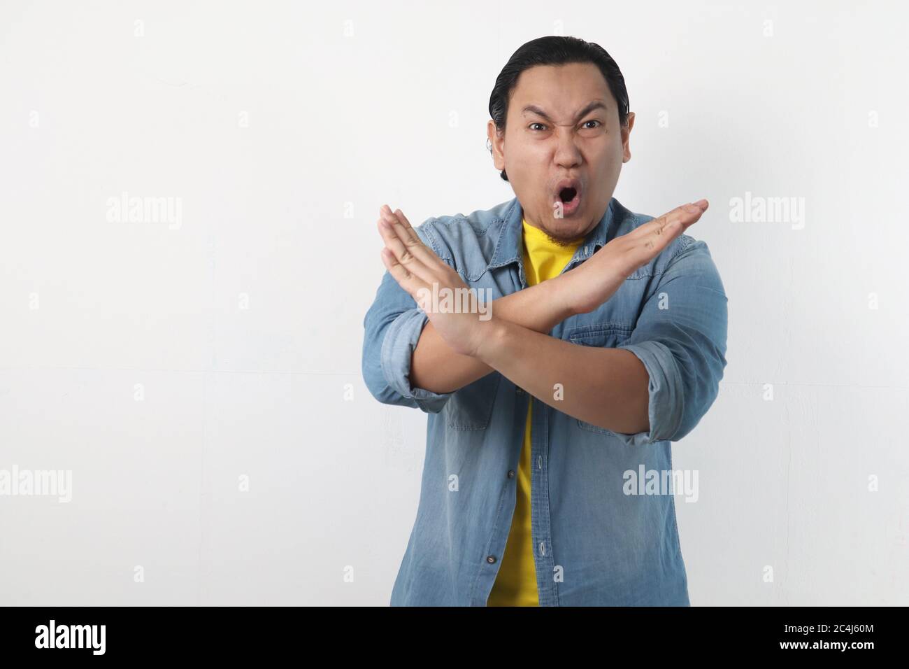 Portrait of young funy angry Asian man shows crossed arms gesture ...
