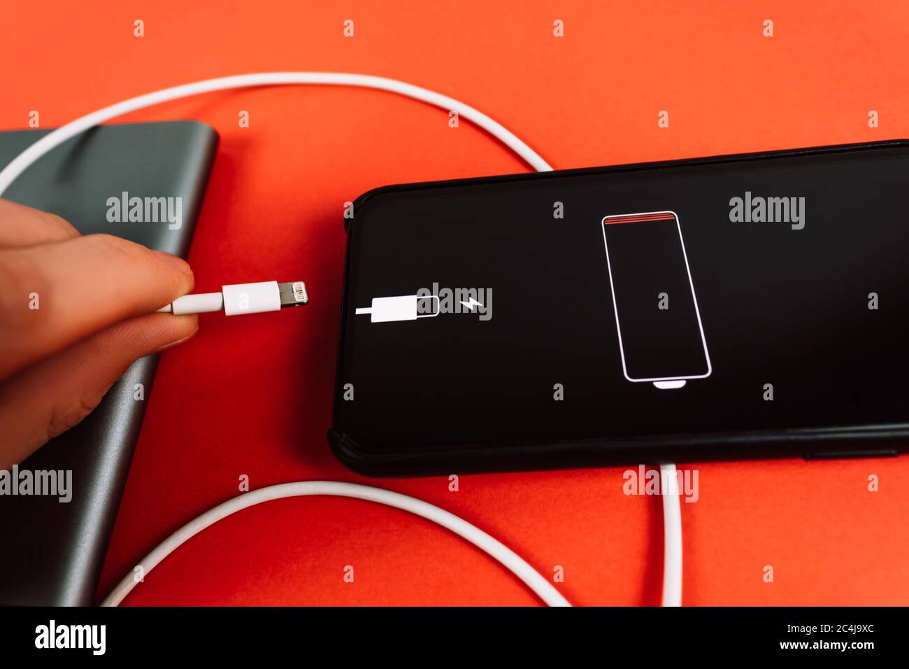 smartphone on a red background connected to charging with a fully ...