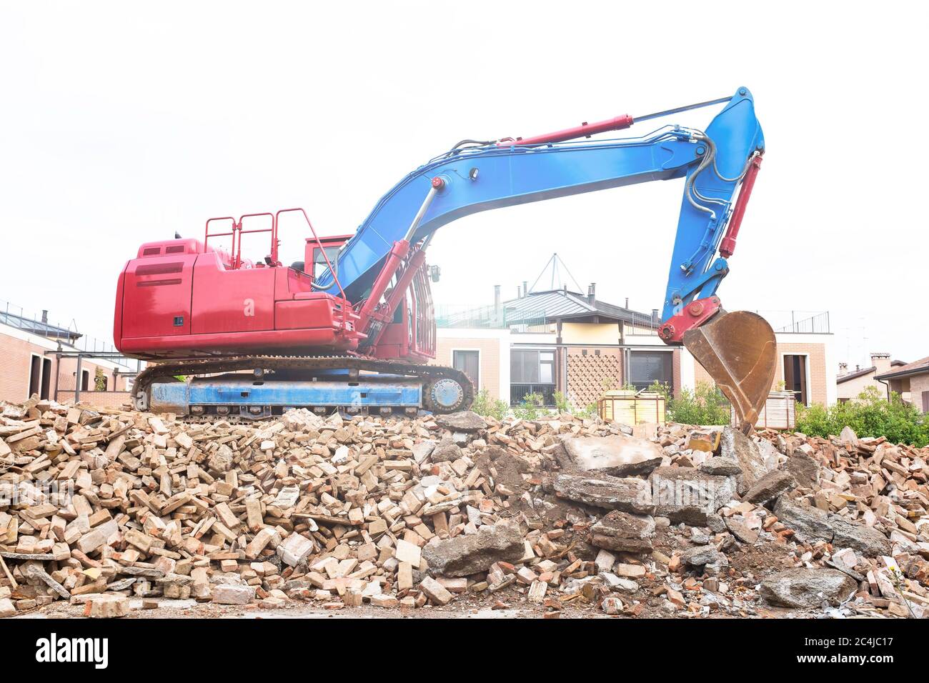 Crawler bulldozer over the rubble of a building in the residential area ...