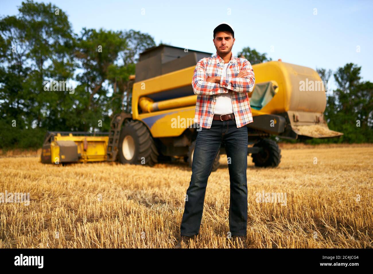 Portrait of proud harvester machine driver with hands crossed on chest ...