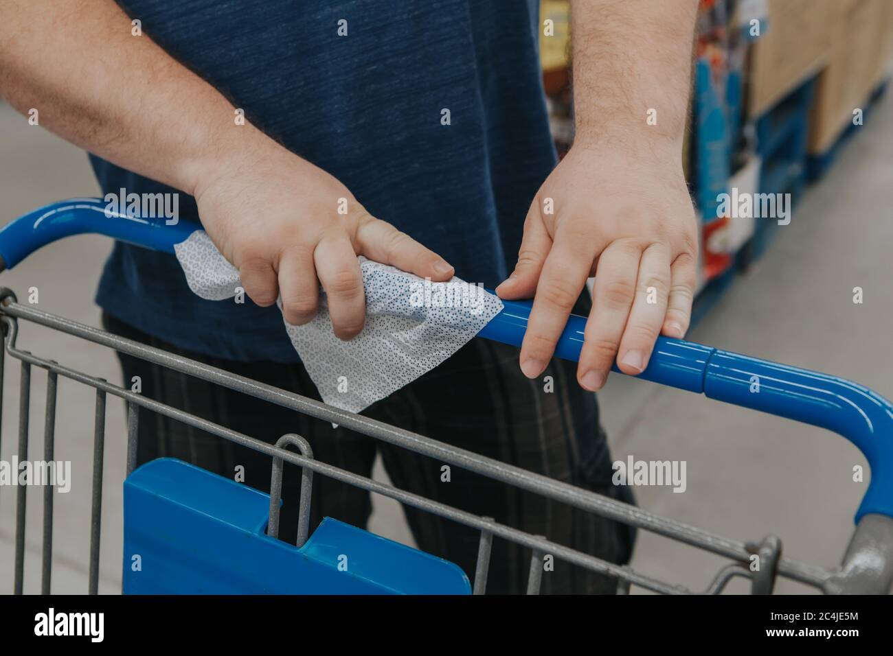 A new normal. Closeup of man hand cleaning shopping cart handle with ...