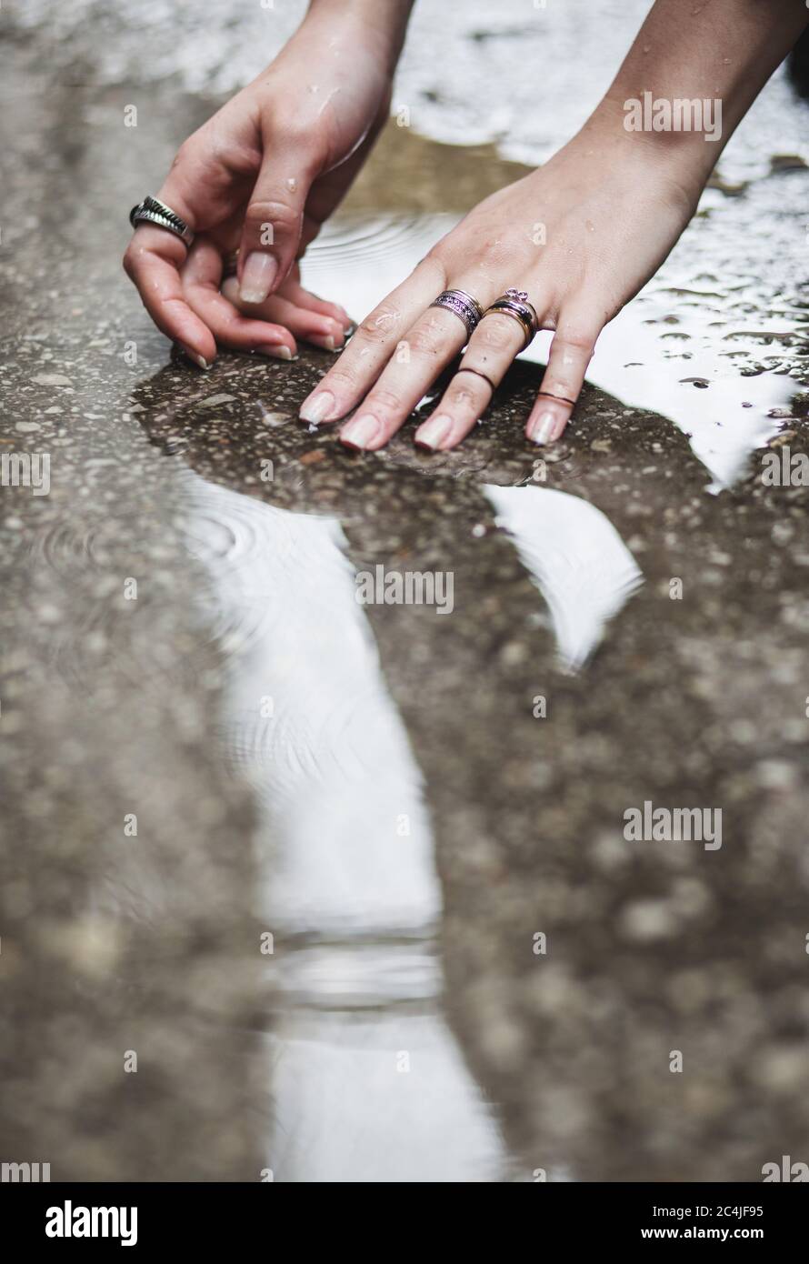 Woman's hands with rings in puddle Stock Photo - Alamy
