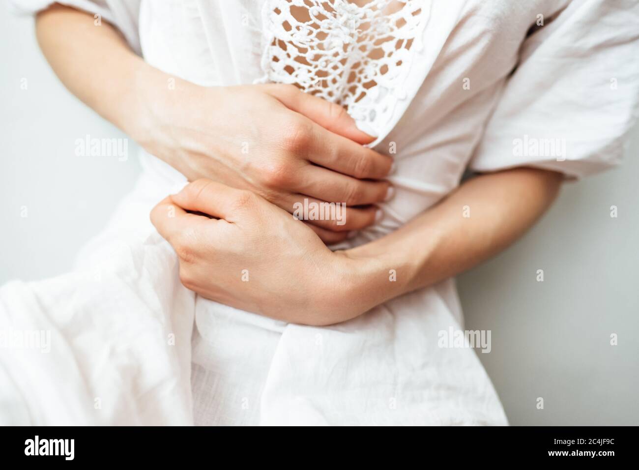 Young woman standing holding belly suffering. Pain Stock Photo - Alamy