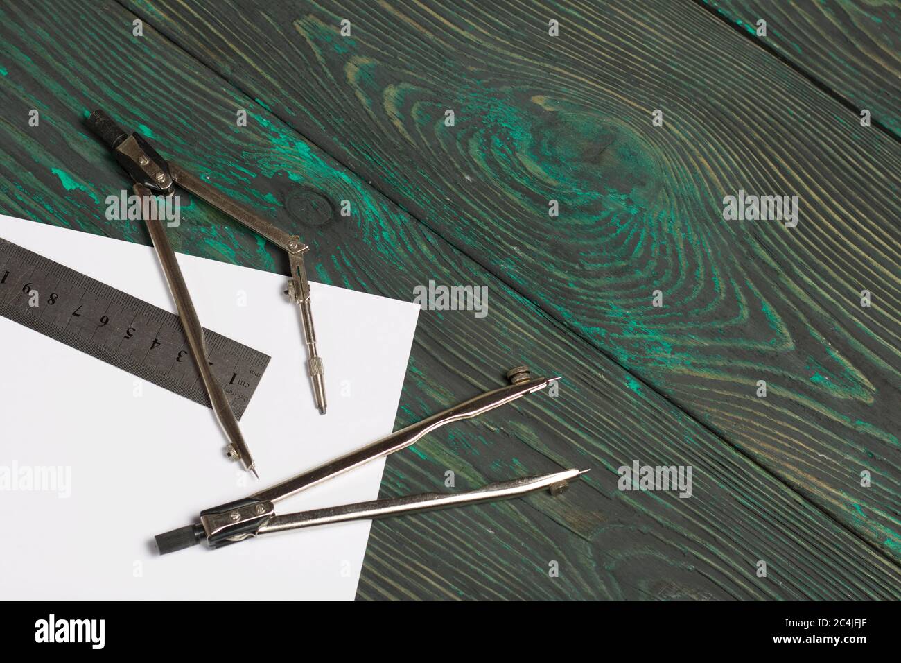 Set for drawing. Two compasses, a metal ruler and a sheet of white ...