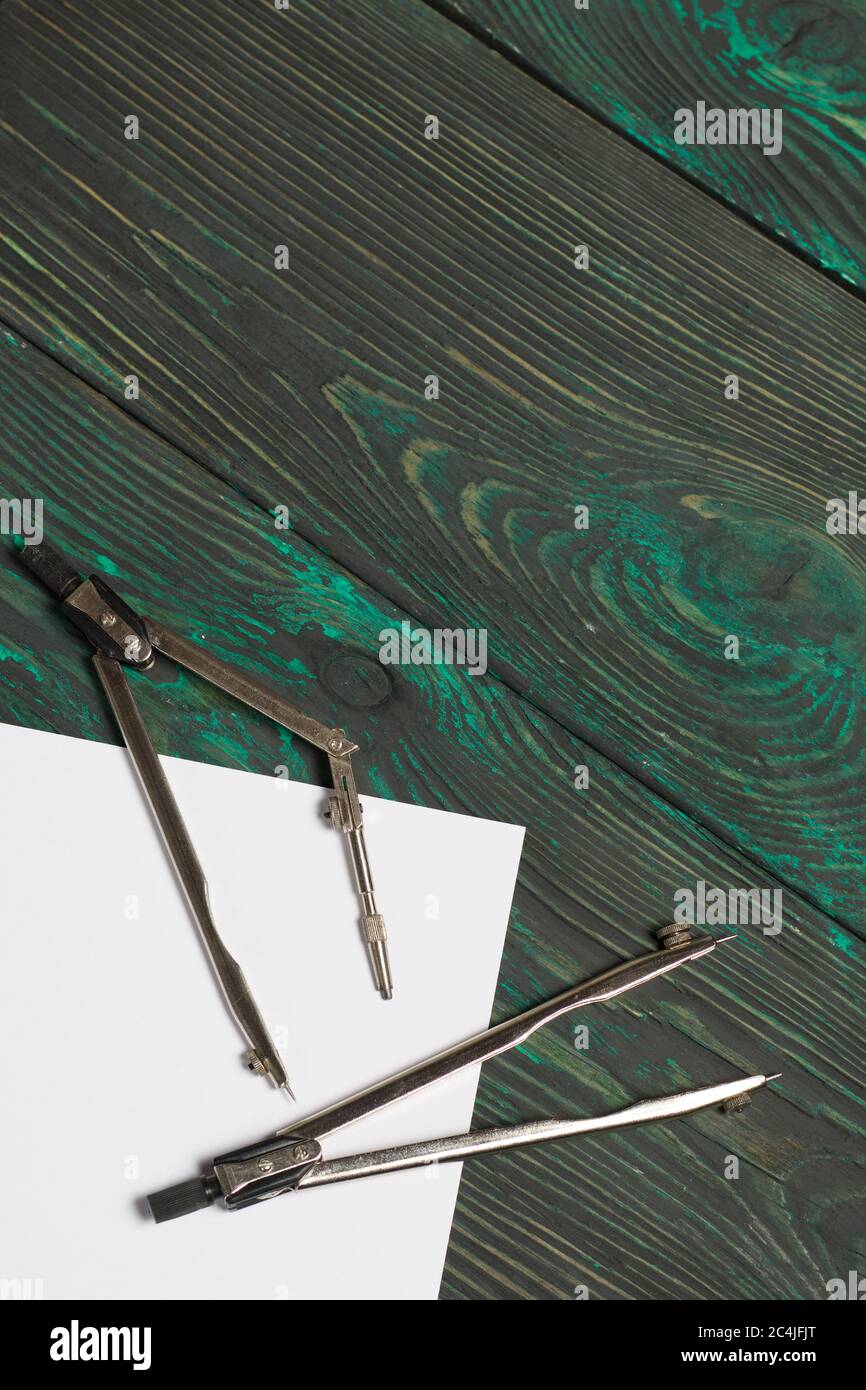 Set for drawing. Two compasses and a sheet of white paper. They lie on ...