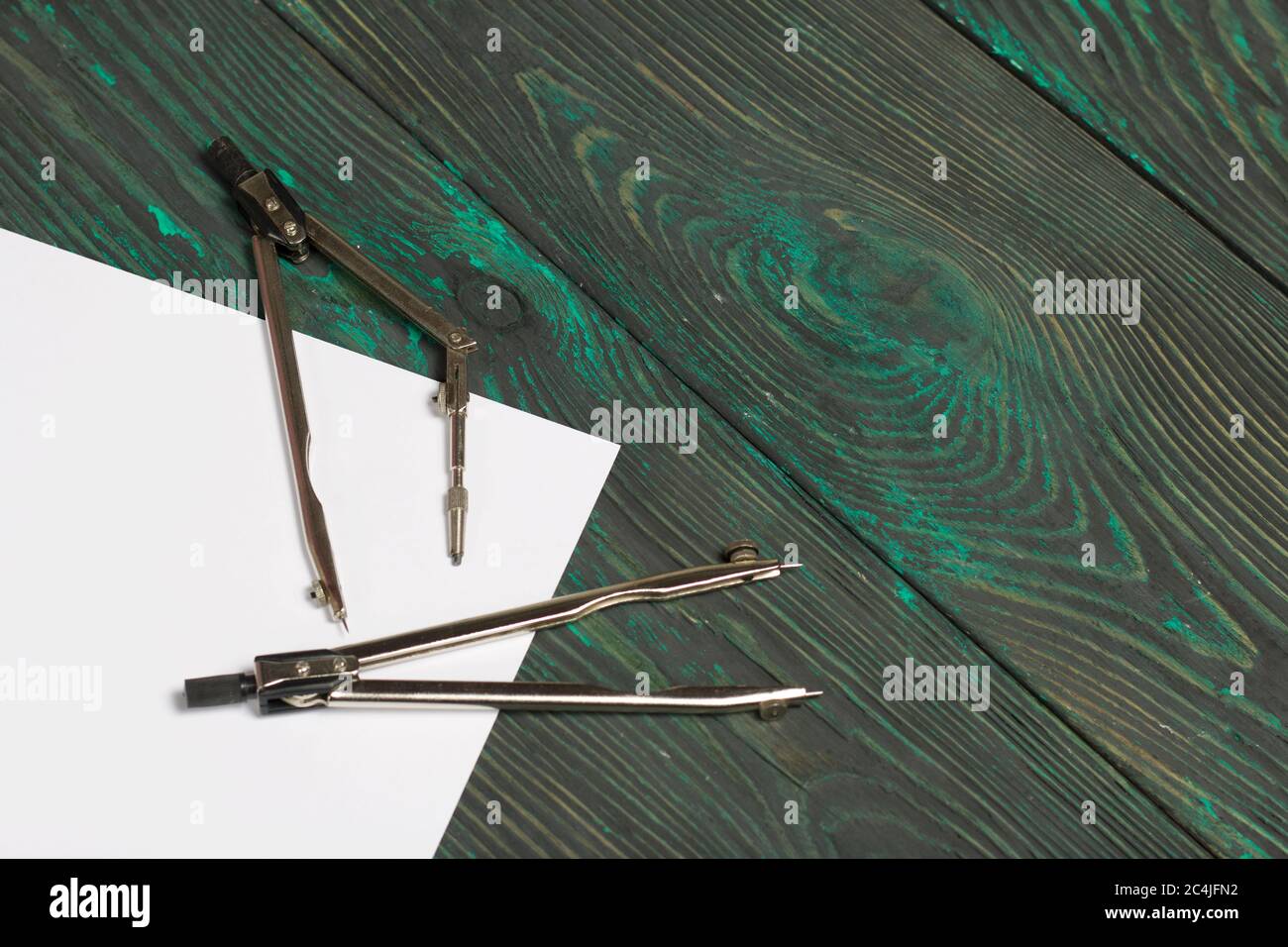 Set for drawing. Two compasses and a sheet of white paper. They lie on ...