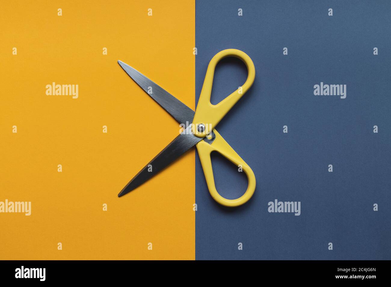 Yellow scissors isolated on a blue and yellow background. Copy space ...