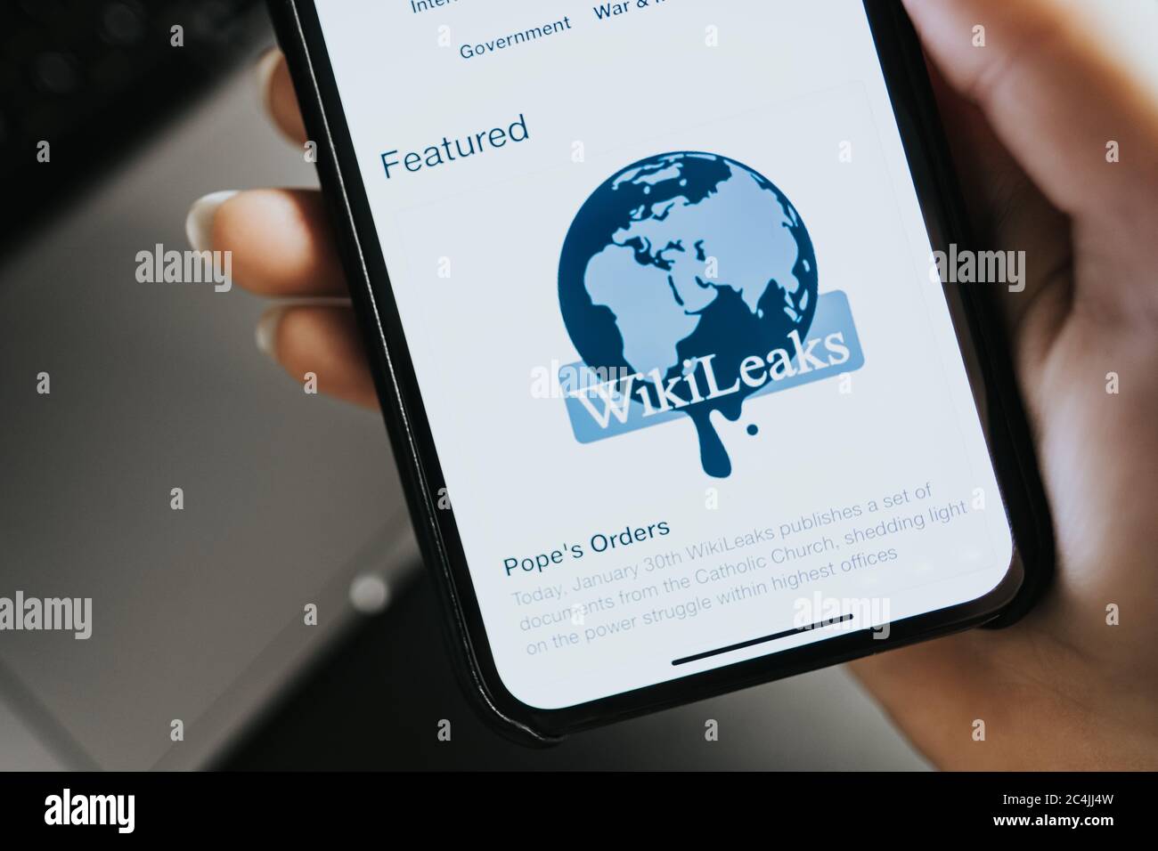 hands holding iPhone X with Wikileaks logo site home page on the screen ...