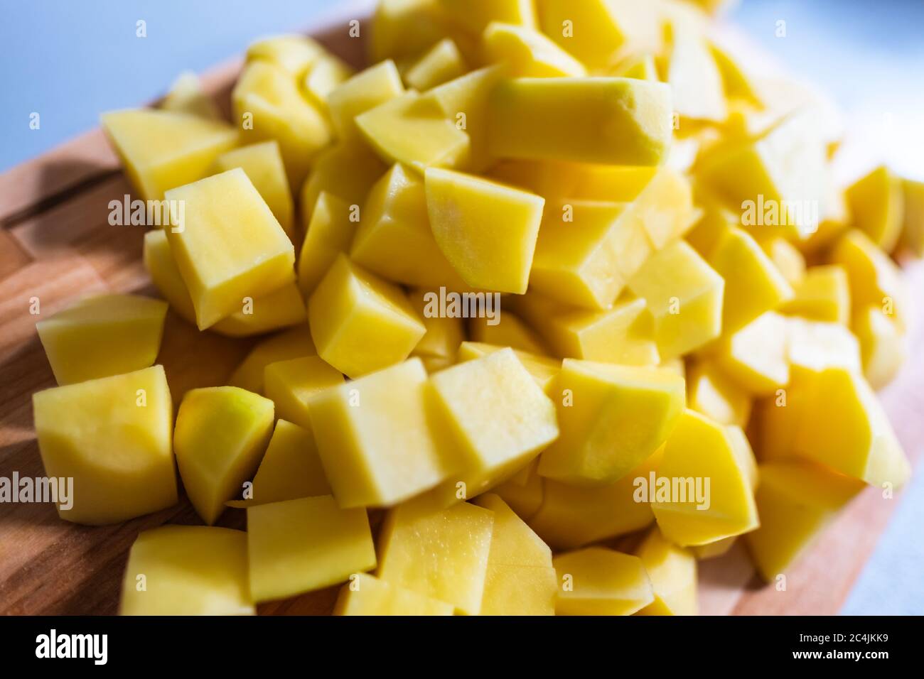 Sliced potato in the shape of a square on a wooden board Stock Photo ...