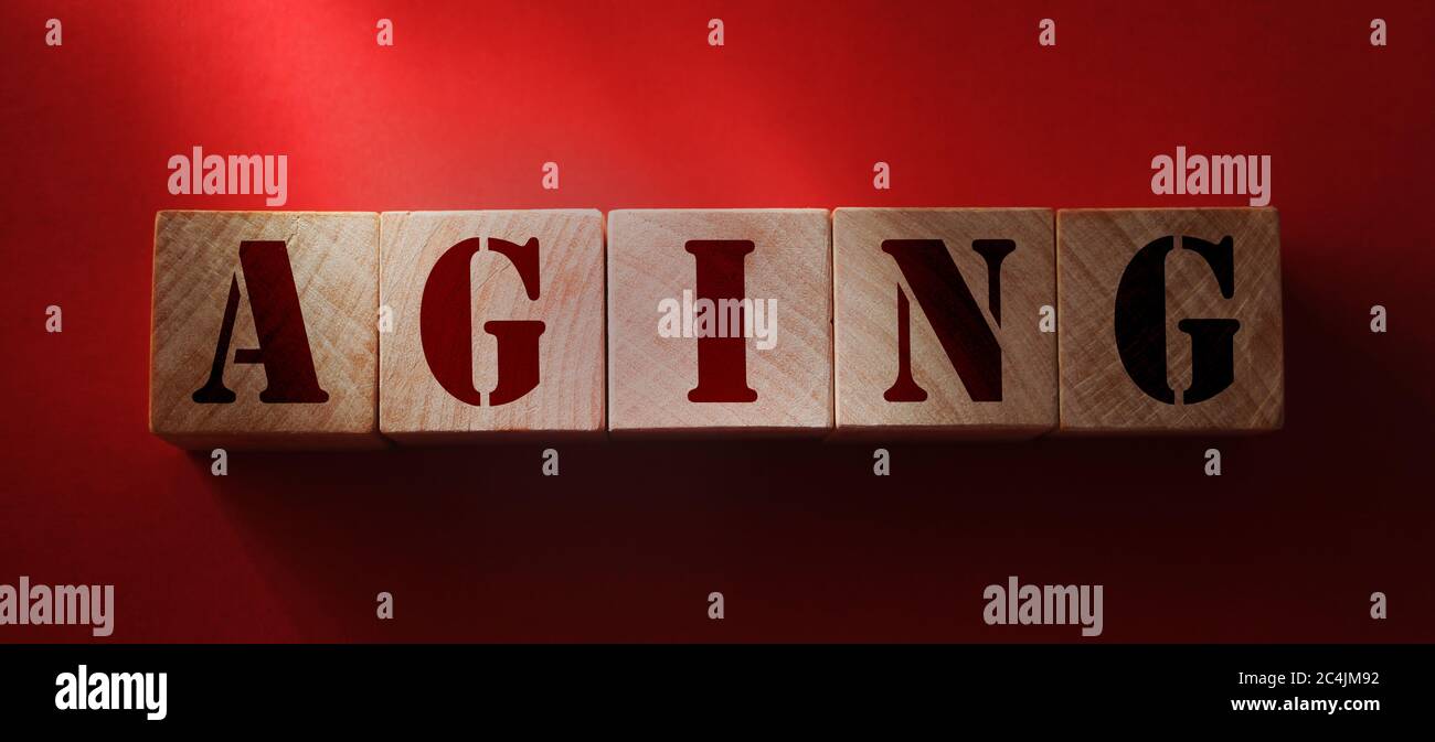 Aging - word from wooden blocks with letters, on red background ...