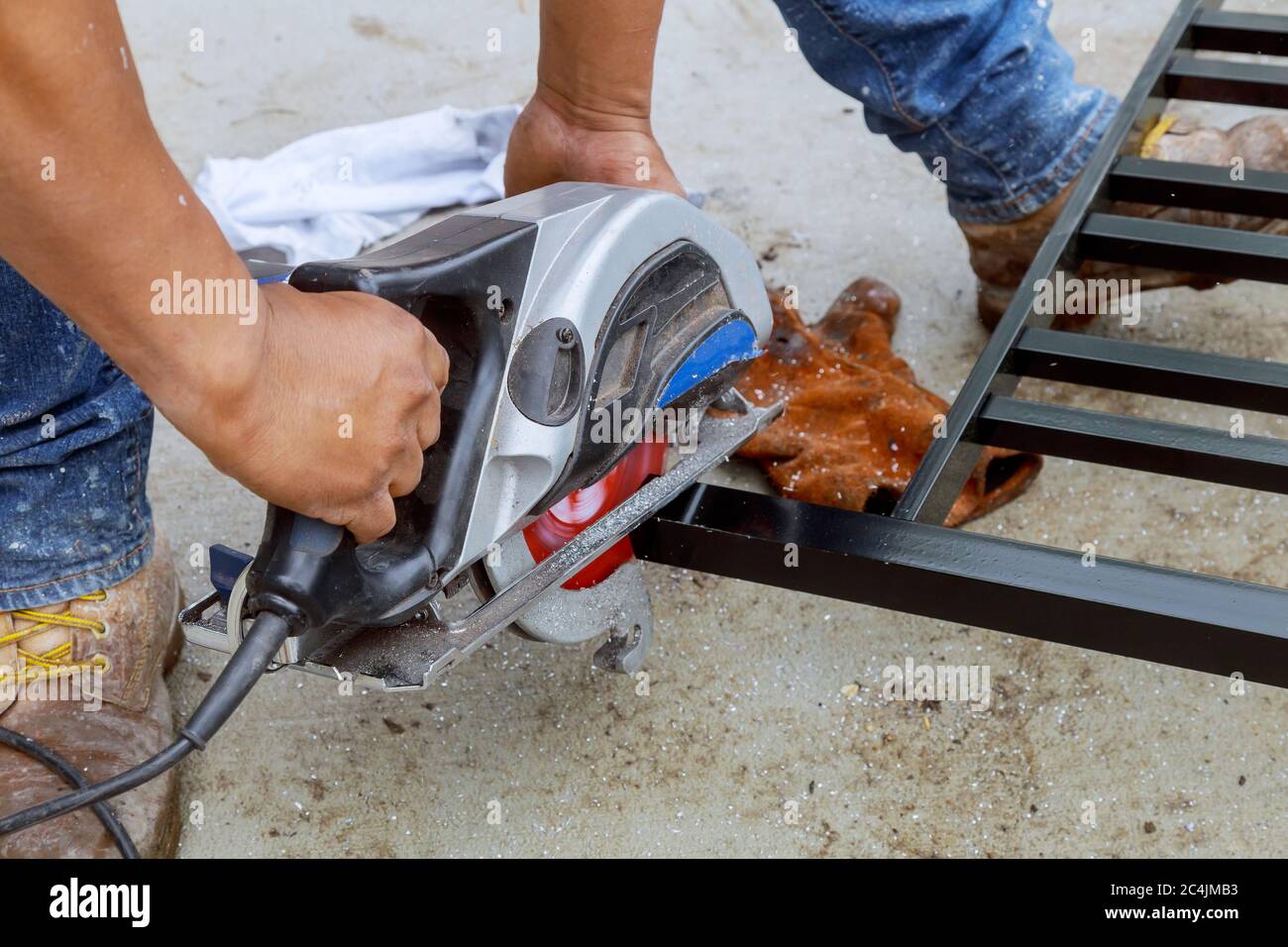 Worker using a circular saw to cut a square metal railings cutters use ...