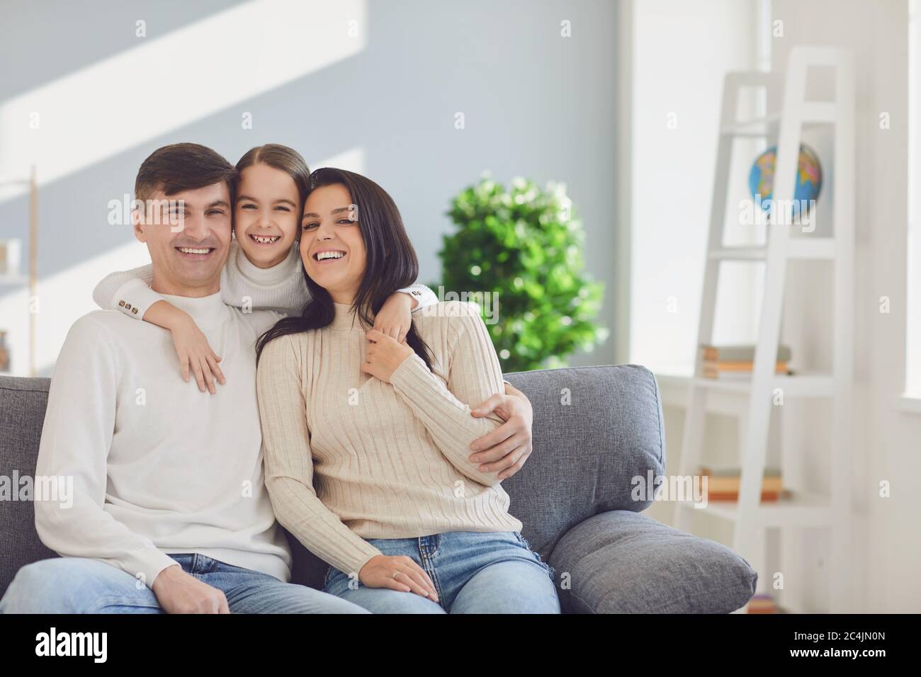Happy family at home. Mother father and daughter sitting on sofa in ...