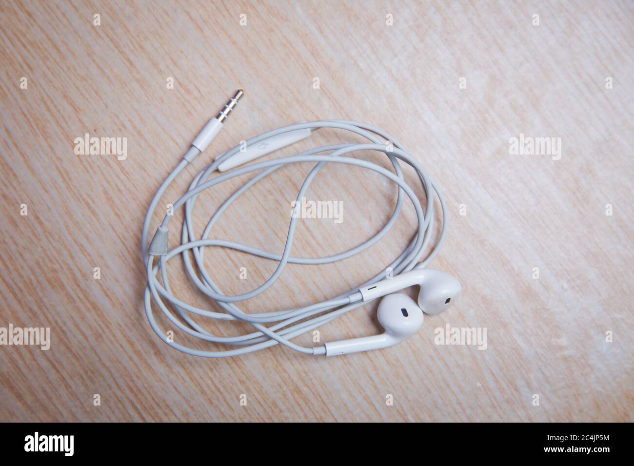 White earphones from the phone . Earbud or earphone top view on wooden ...