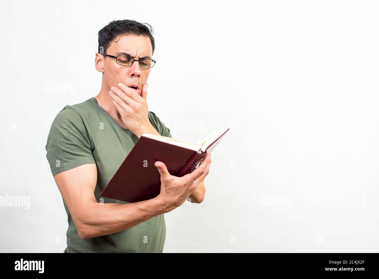Man with glasses, very concentrated on reading a book. Mid shot. White ...
