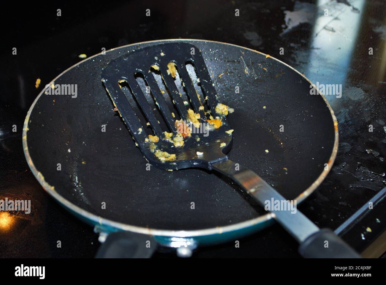 Dirty spatula sitting in an empty skillet on the stove after cooking ...