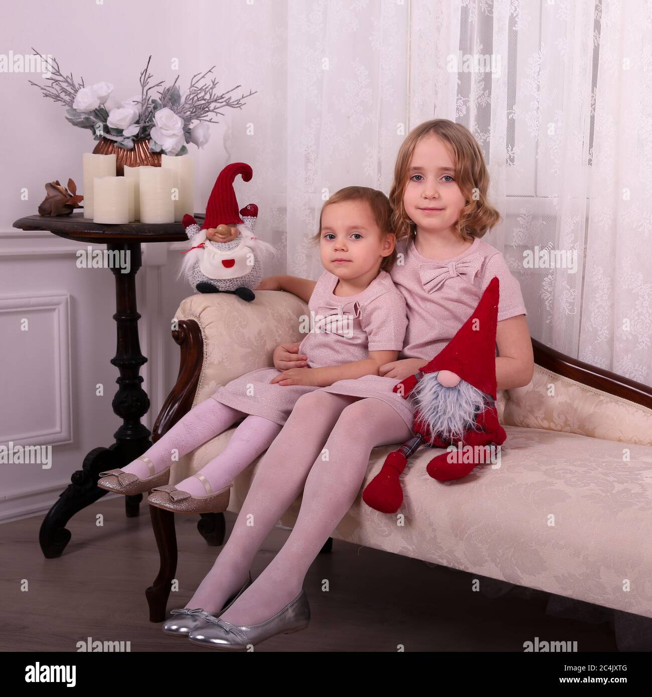 Two little sisters are waiting for Christmas. Girls are sitting near ...