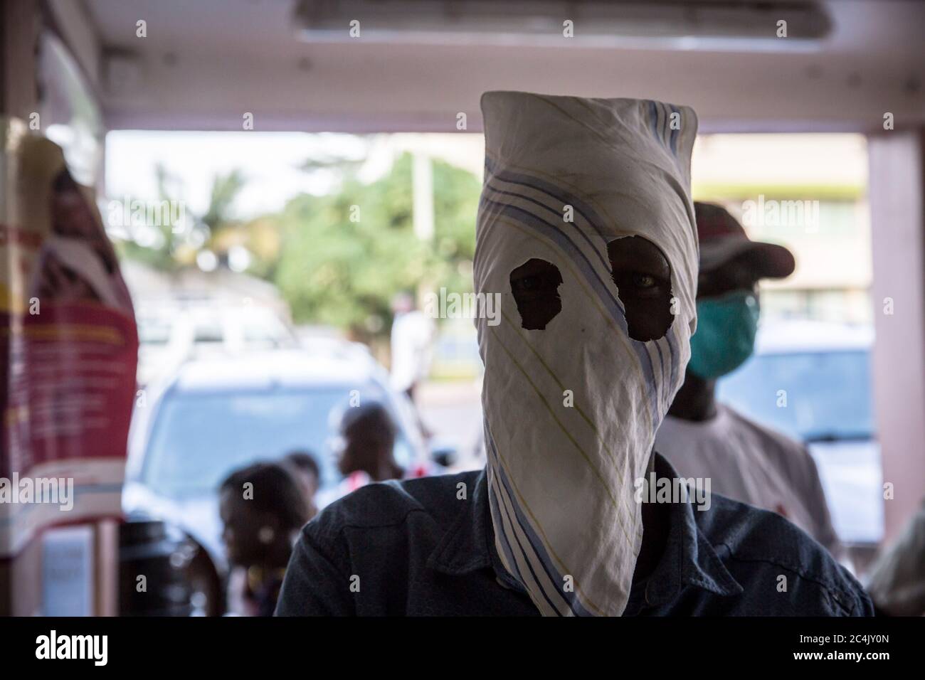 A man wearing an unusual mask poses outside a supermarket in Gulu ...