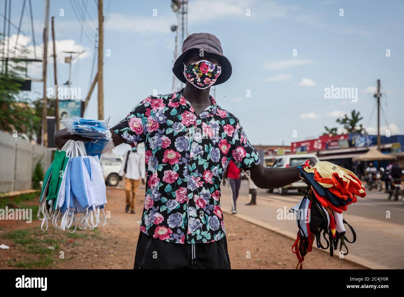 A vendor sells masks in Gulu poses on the street.Many hawkers now sell ...