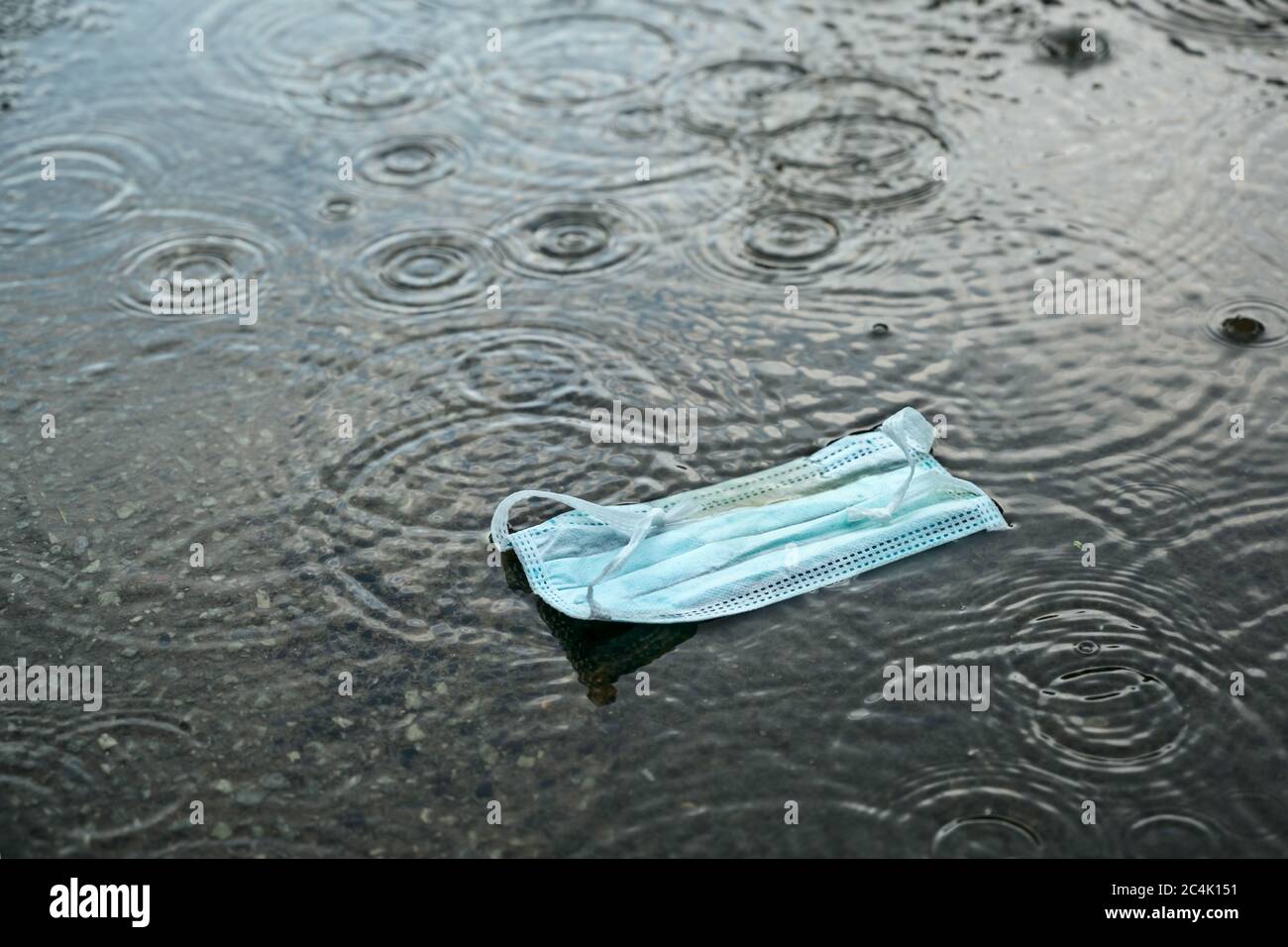 Surgical face mask against coronavirus infection discarded on the black ...