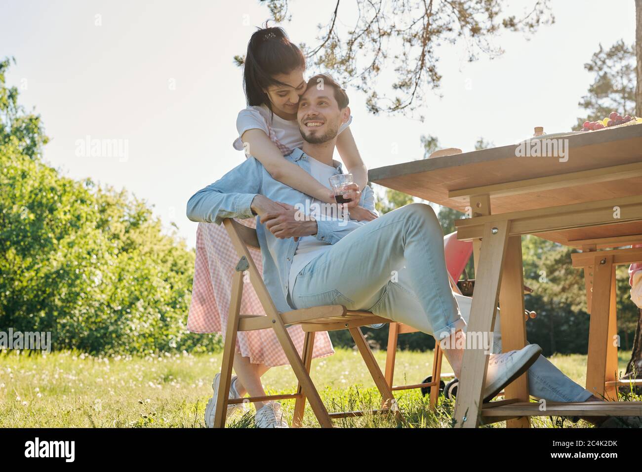 Happy young affectionate woman with glass of red wine embracing her ...