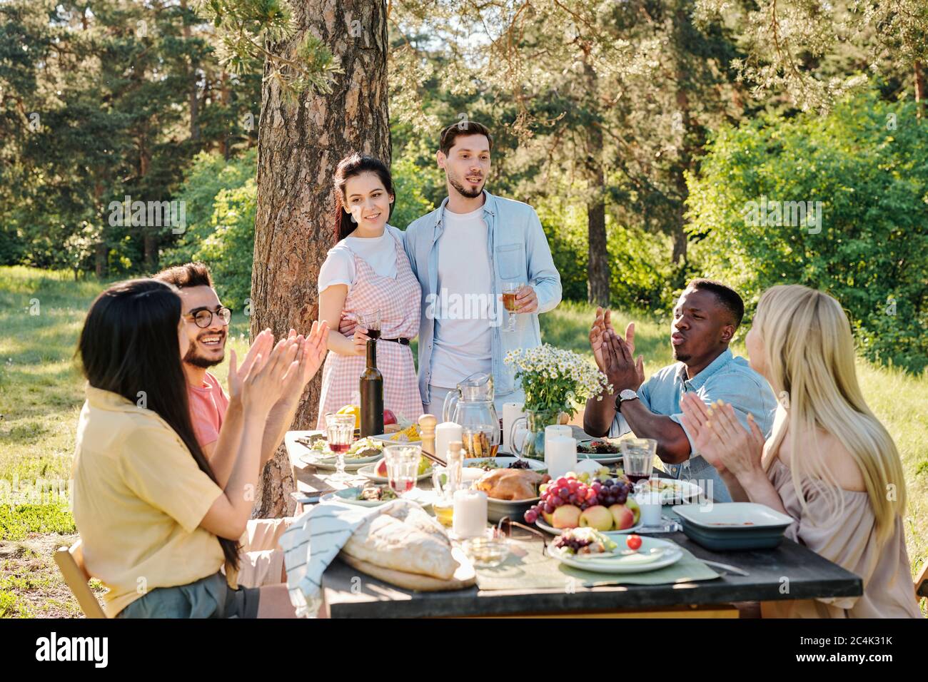 Two pairs of young intercultural dates clapping hands while ...