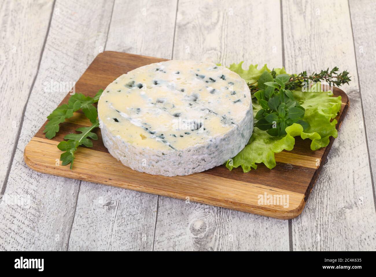 Round blue cheese with salad and basil Stock Photo - Alamy