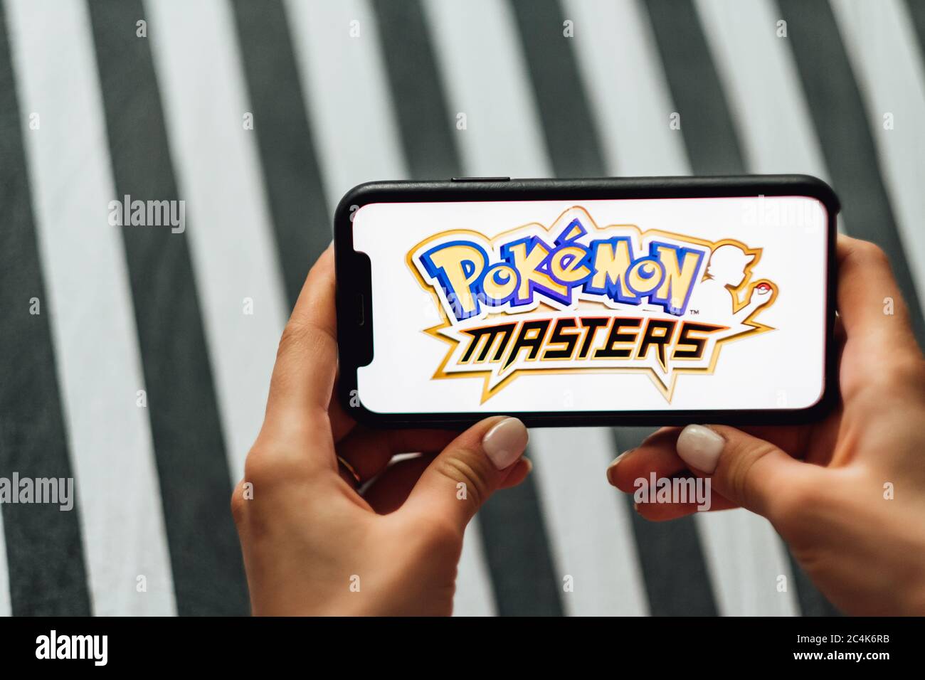 Hands holding iPhone with Pokemon masters on the screen Stock Photo - Alamy